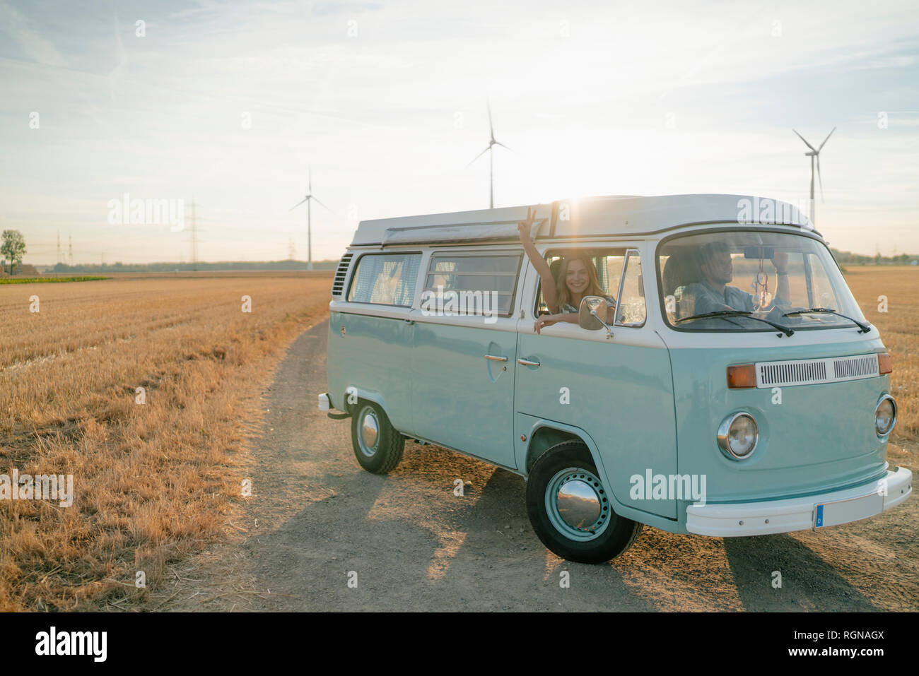 Happy woman making victory hand sign out of window of a camper van with ...