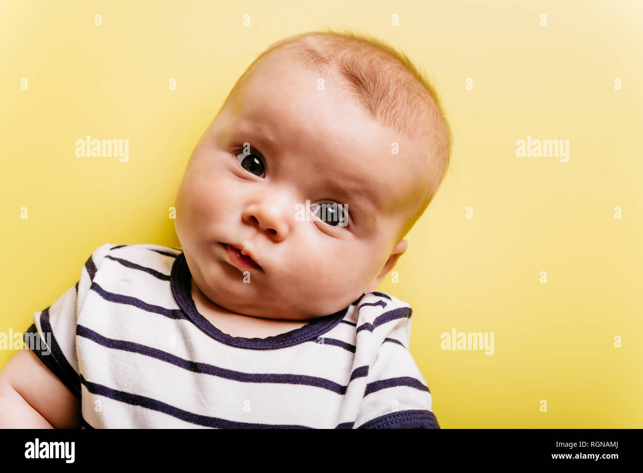 Portrait of sceptical baby girl in front of yellow background Stock ...