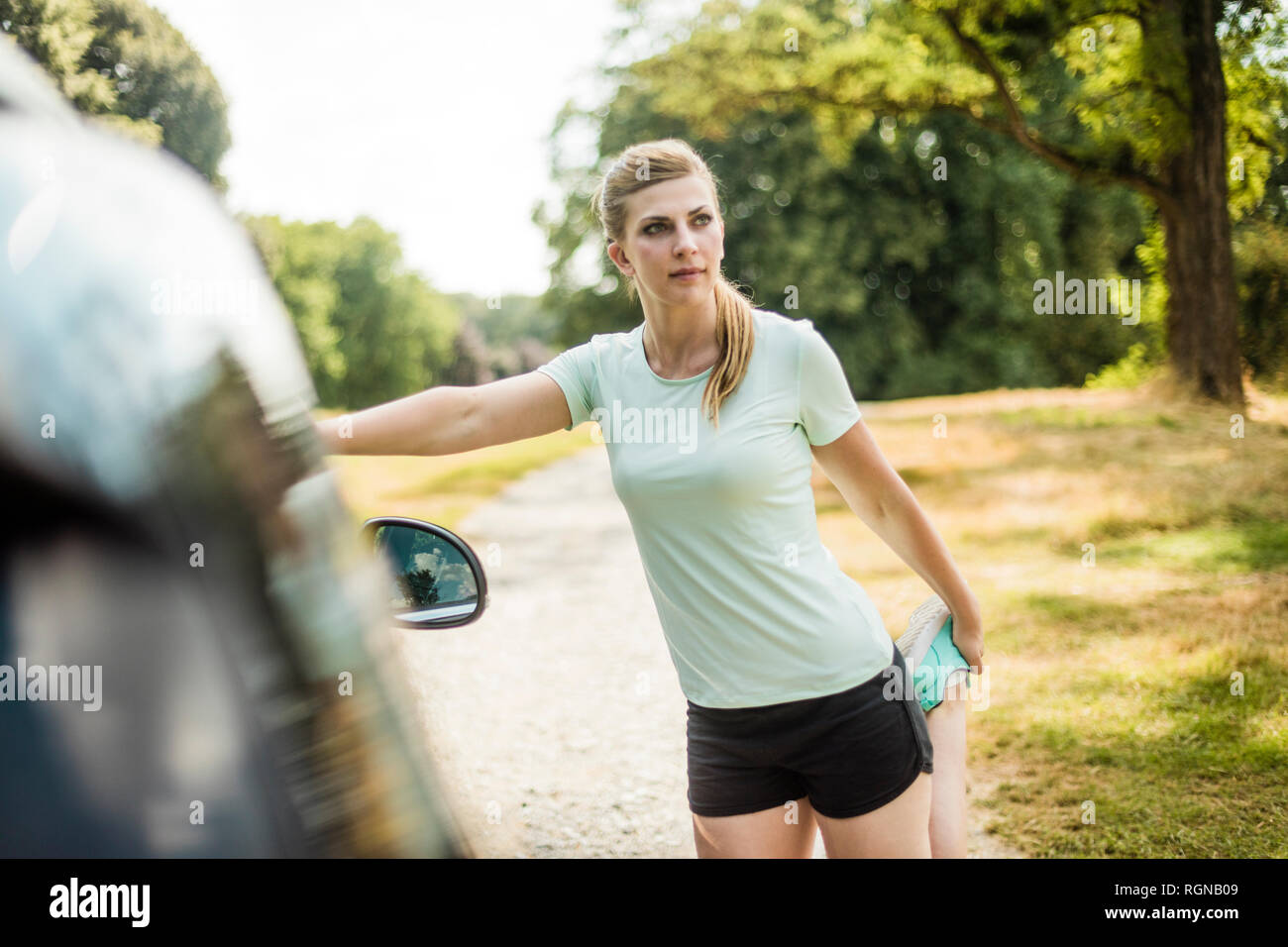 Sportive young woman stretching at a car in a park Stock Photo - Alamy