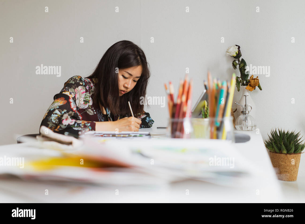 Illustrator painting at work desk in an atelier Stock Photo - Alamy