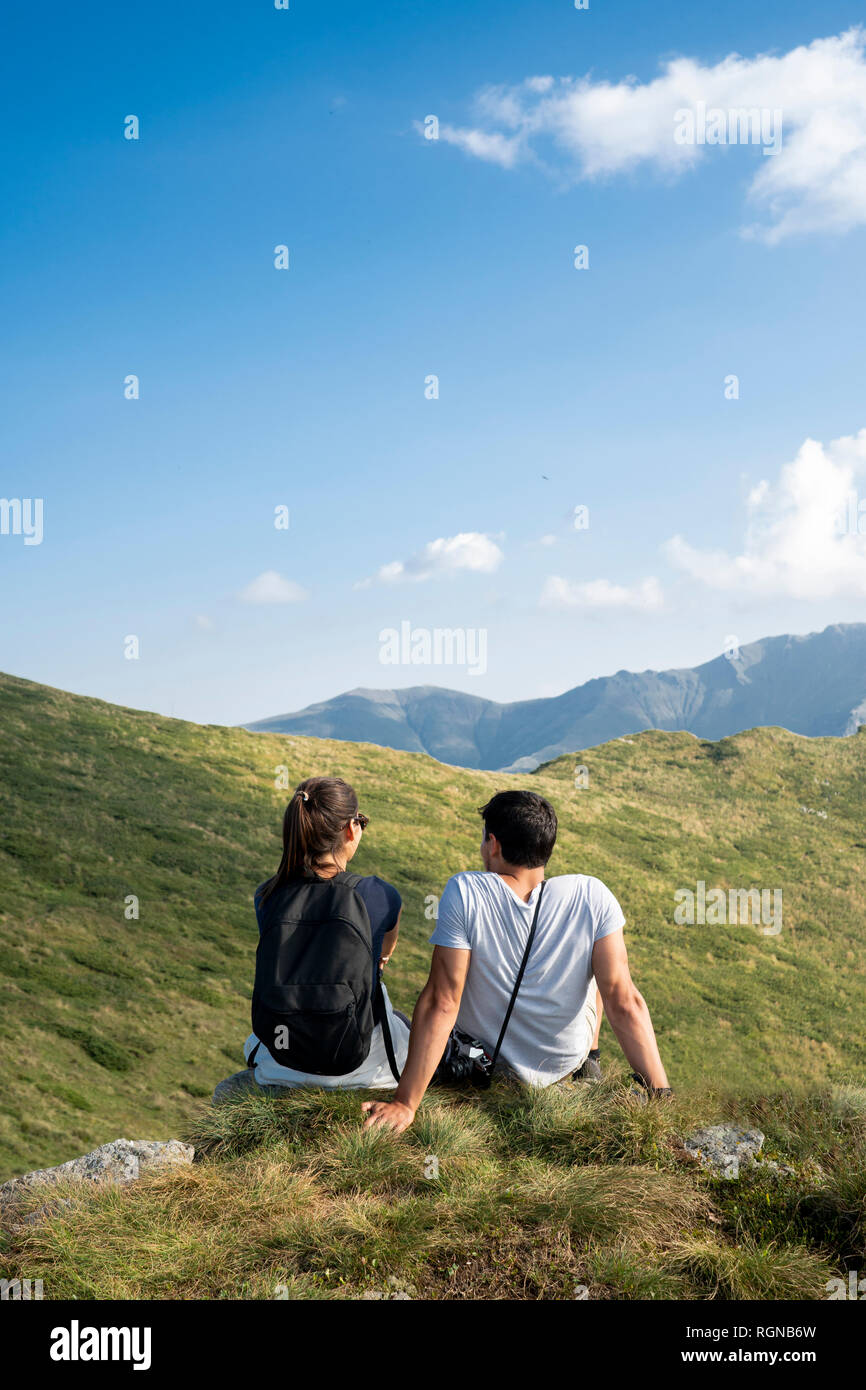 Bulgaria, Balkan Mountains, couple sitting on viewpoint, rear view ...