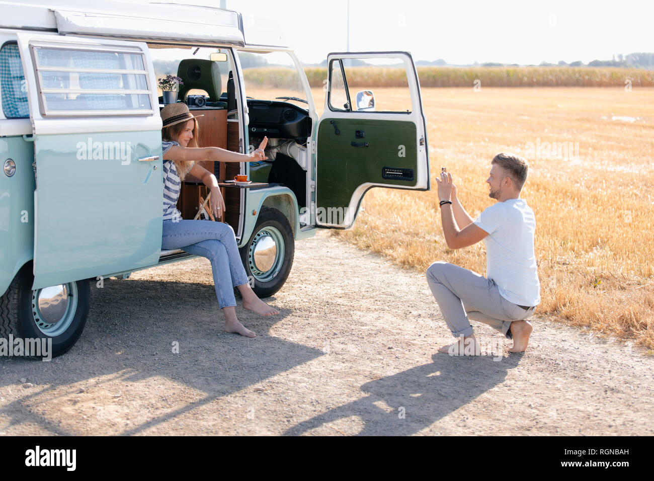 Young man taking cell phone picture of girlfriend inside camper van in ...