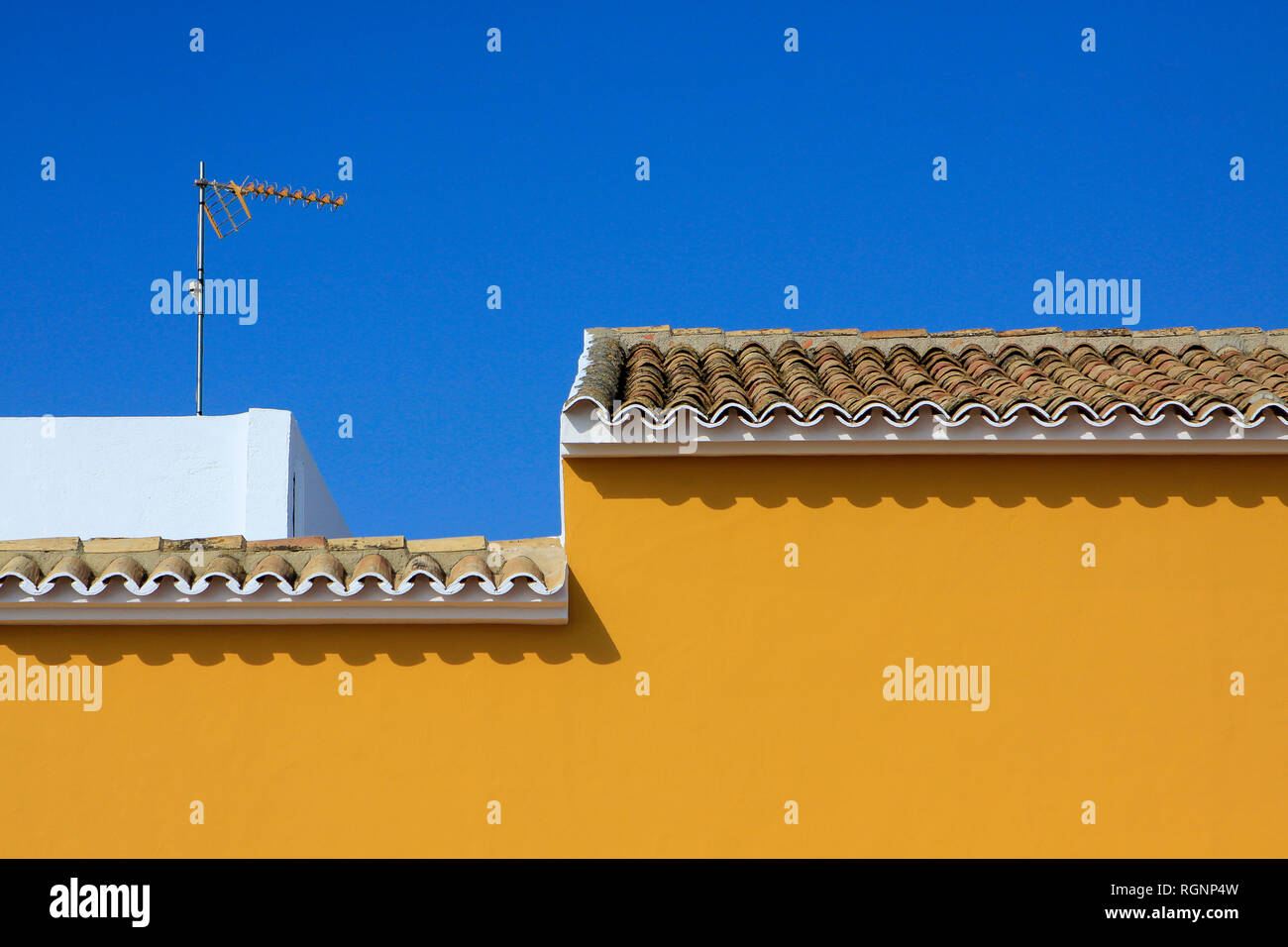 Mediterranean ochre wall and traditional rooftop tiles with brilliant ...