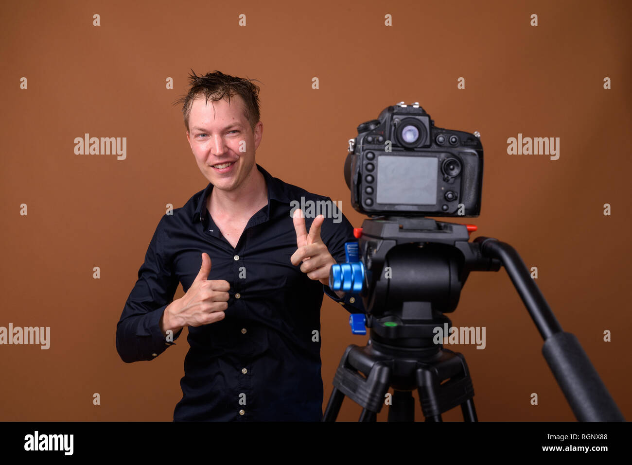 Happy man influencer vlogging with DSLR camera in studio Stock Photo ...