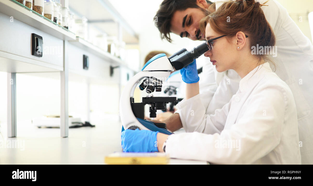 Woman watching through microscope hi-res stock photography and images ...