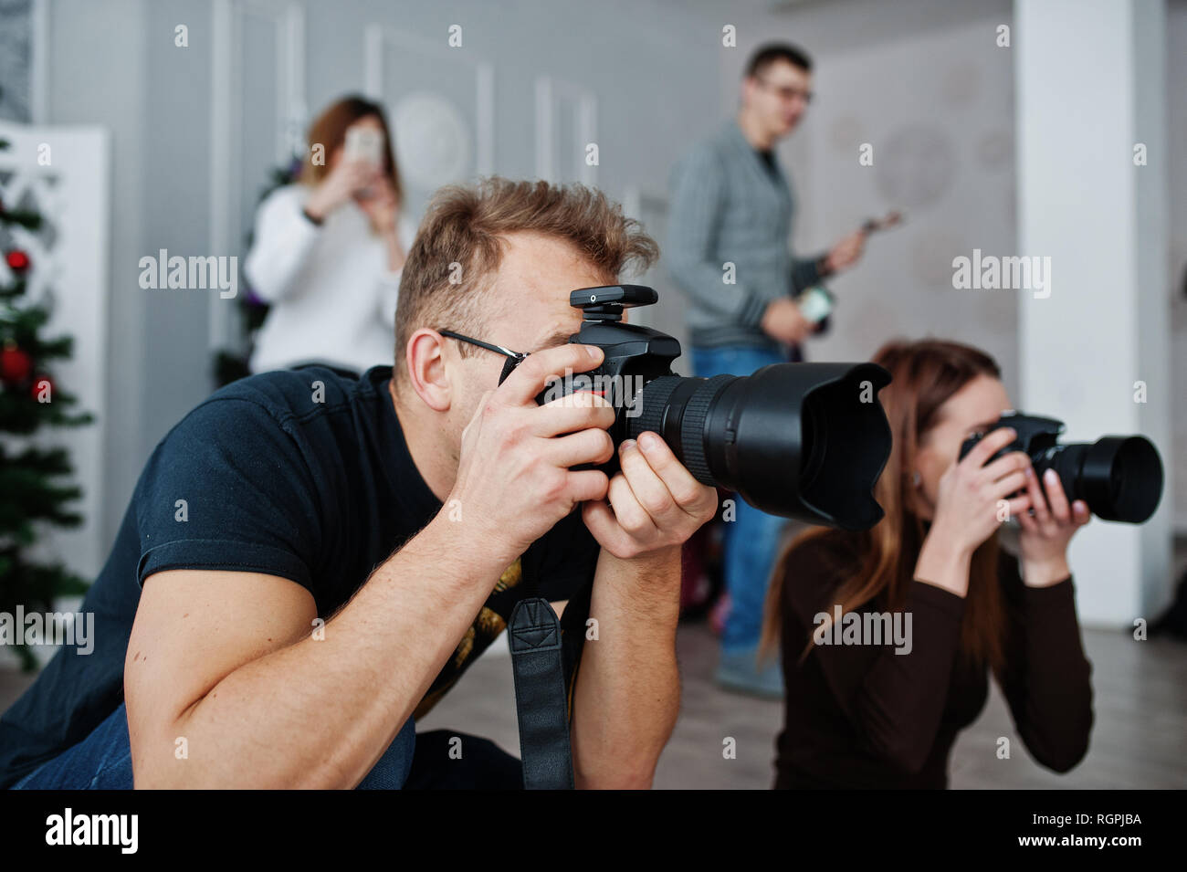 The team of two photographers shooting on studio behind another three ...