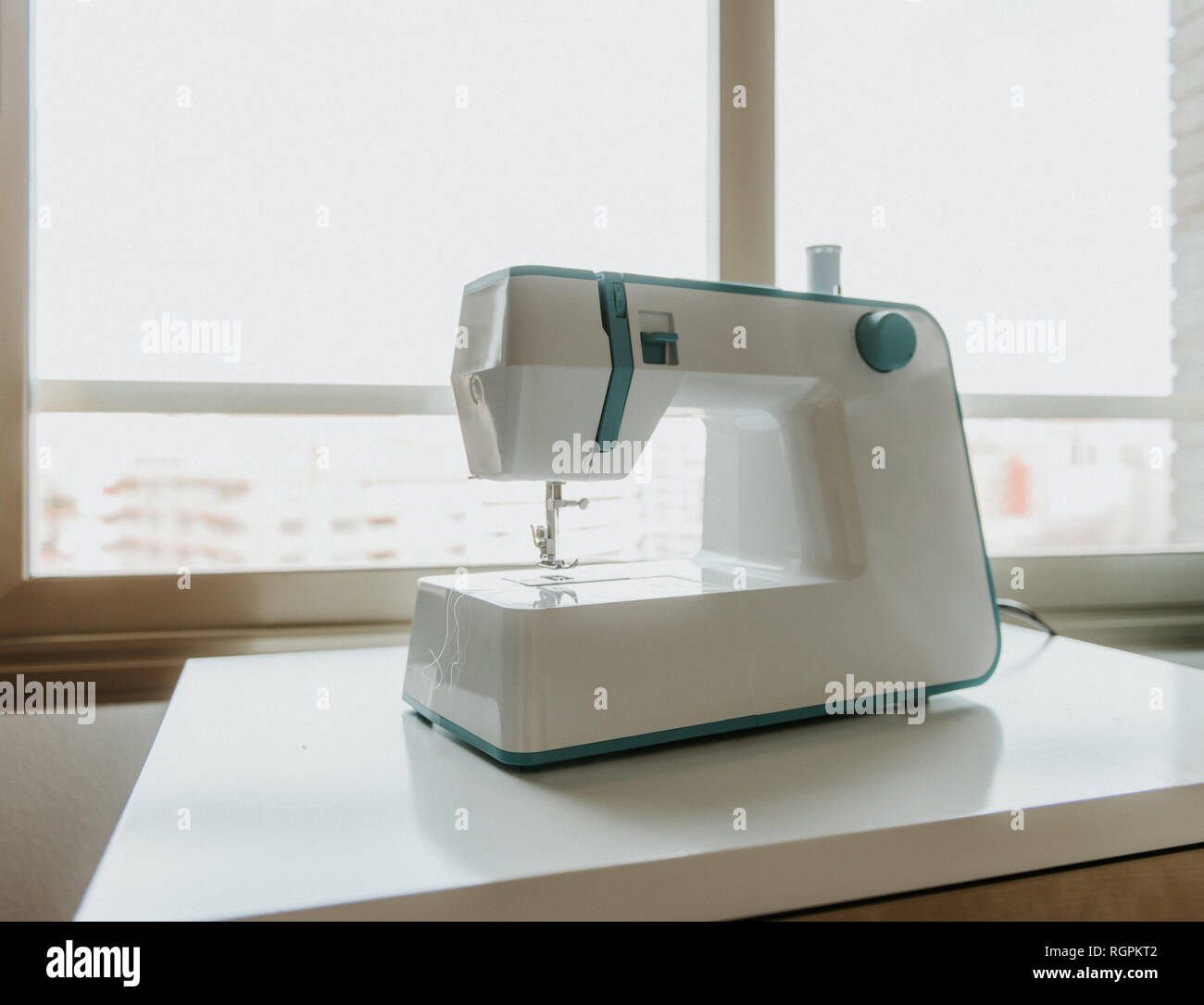 Contemporary sewing machine standing on small table near window in ...