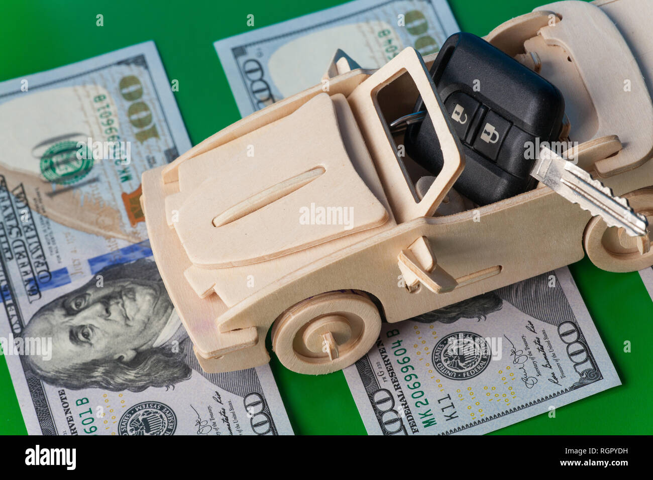 Wooden Toy Car and key vehicle with money on green background. Concept ...