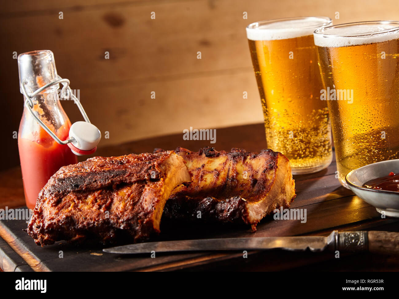 Spicy seasoned grilled spare ribs with two tall glasses of cold beer ...