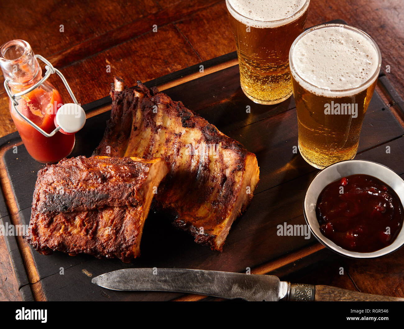 Two portions of spicy grilled spare ribs served with cold beers and a ...
