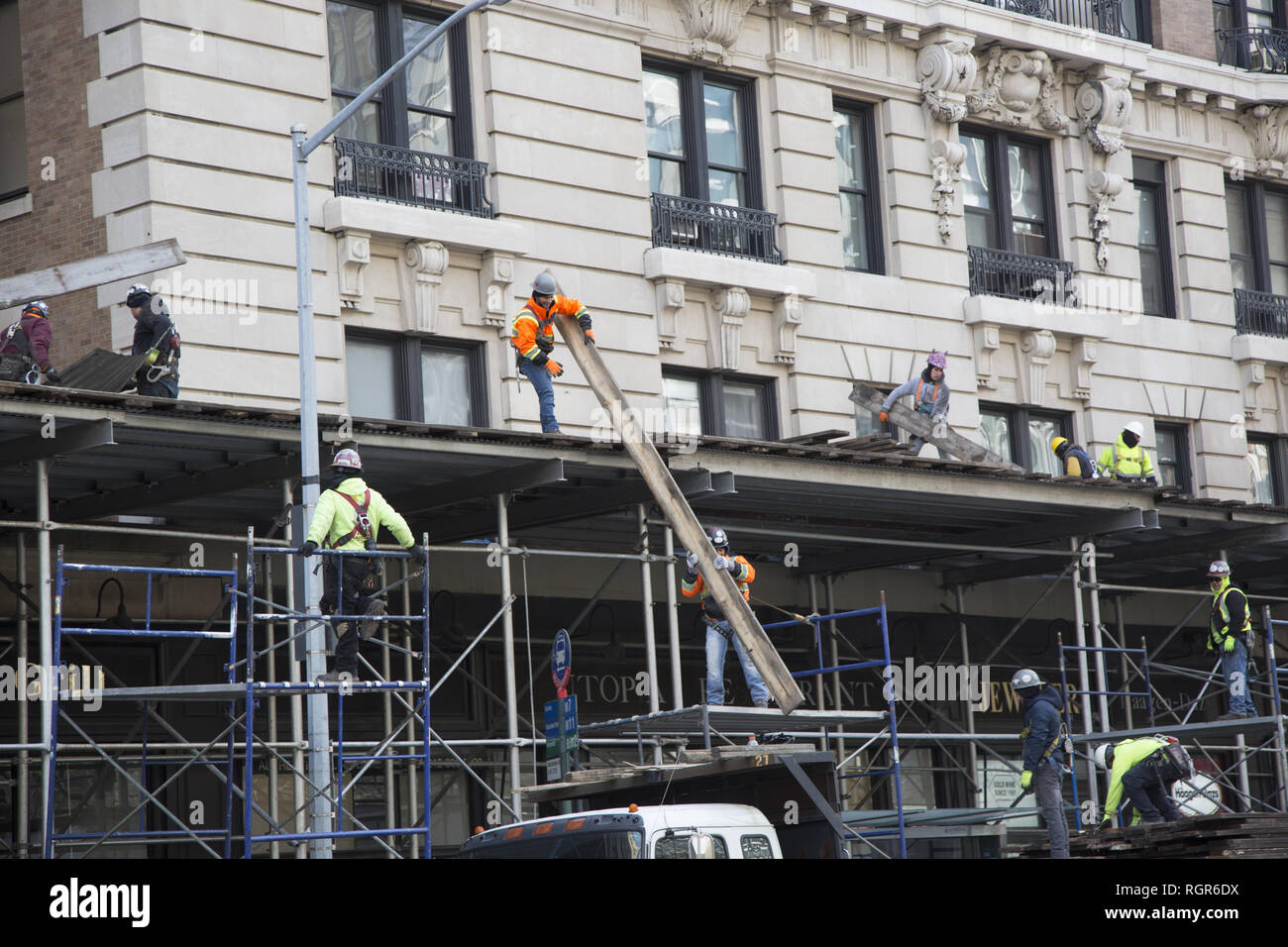 Construction workers put up scaffolding for a building renovation as ...