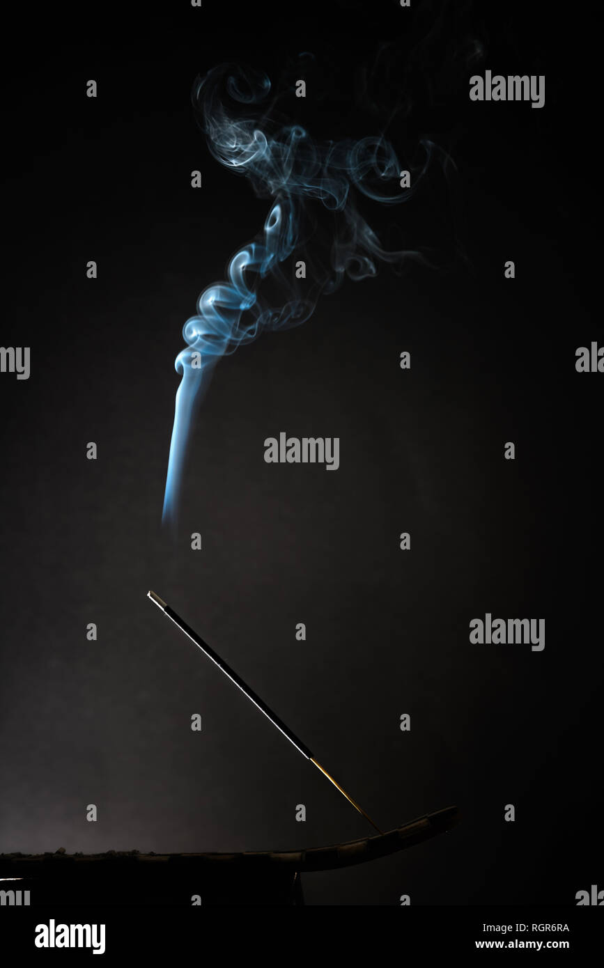 Smoking incense stick with smoke going up on Black Background. Pure ...