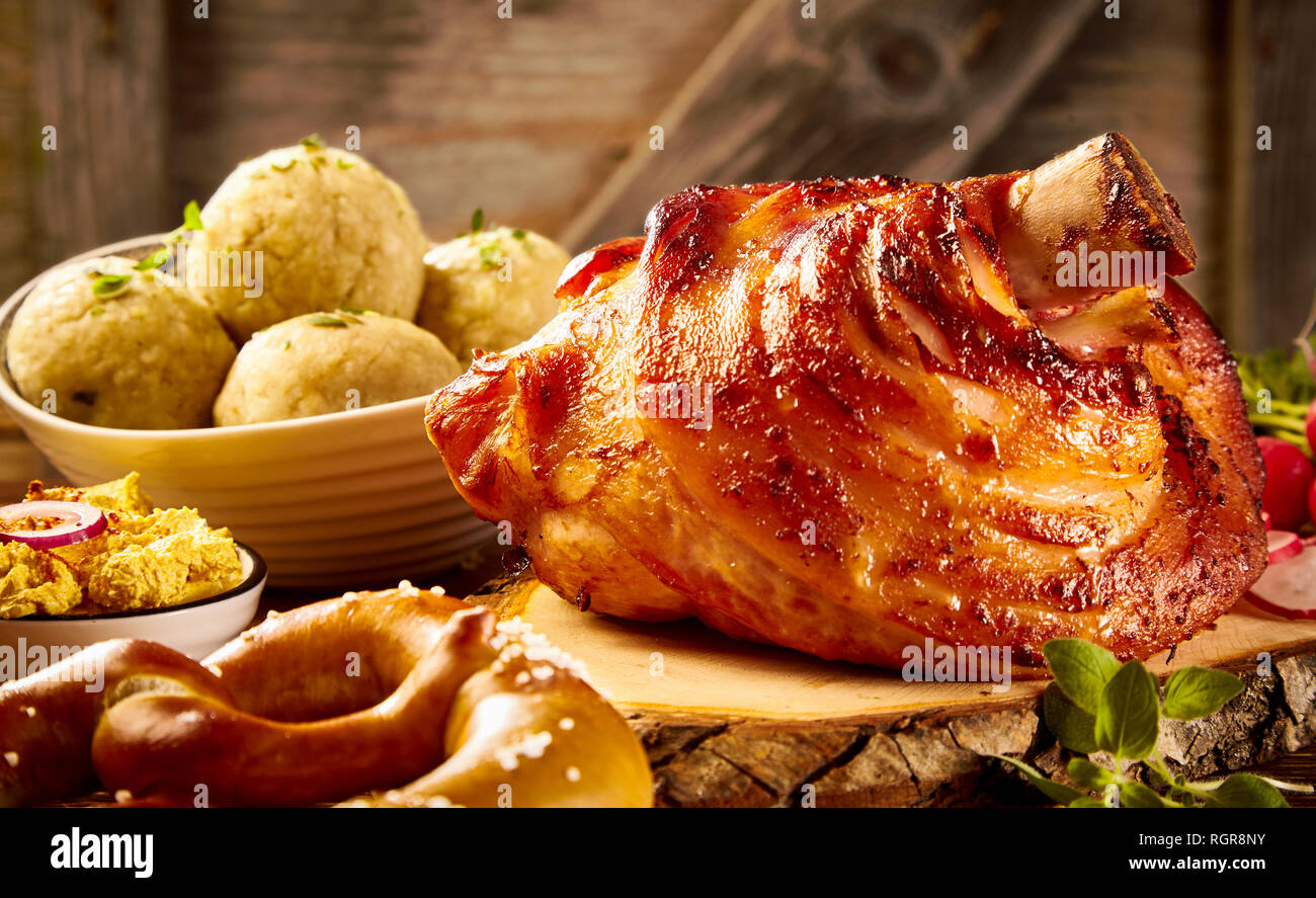 Glazed roasted pork hock or knuckle served with a pretzel and bowl of ...
