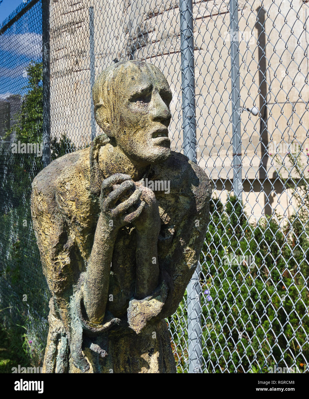 Bronze sculpture of frail Irish immigrant, hands clasped in prayer ...
