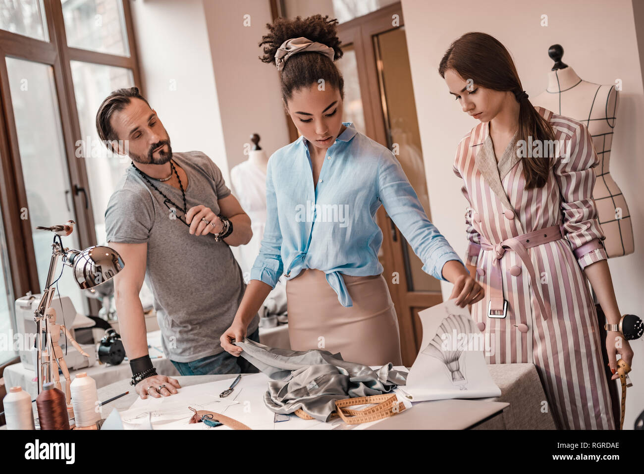 African designer touches material. Group of three people at design ...
