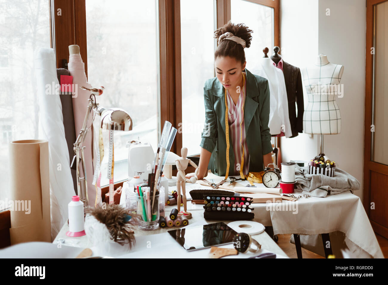 Inside work process. Woman designer standing with measure tape at her ...