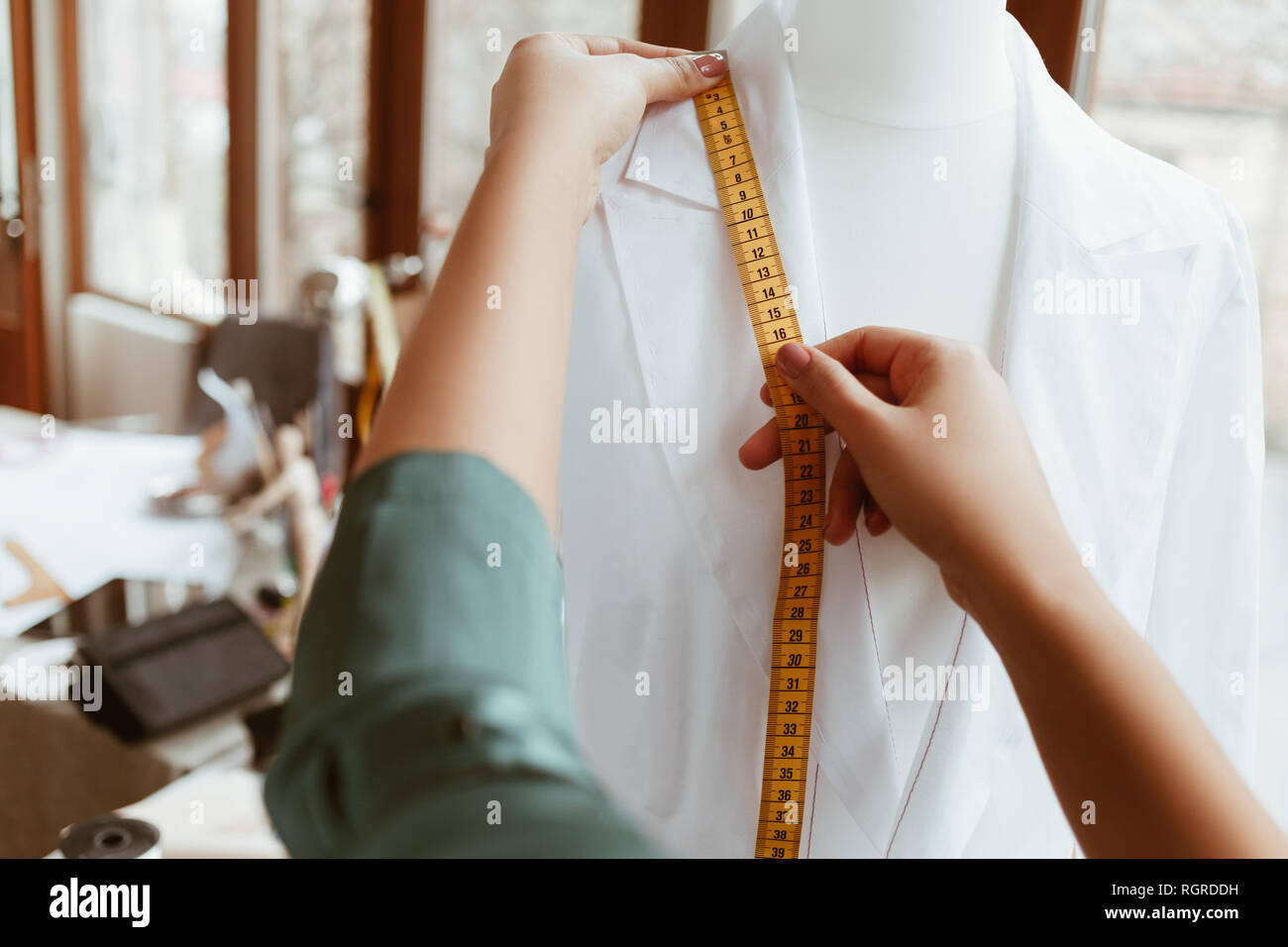 The main thing is right size. Woman designer is measuring white shirt ...