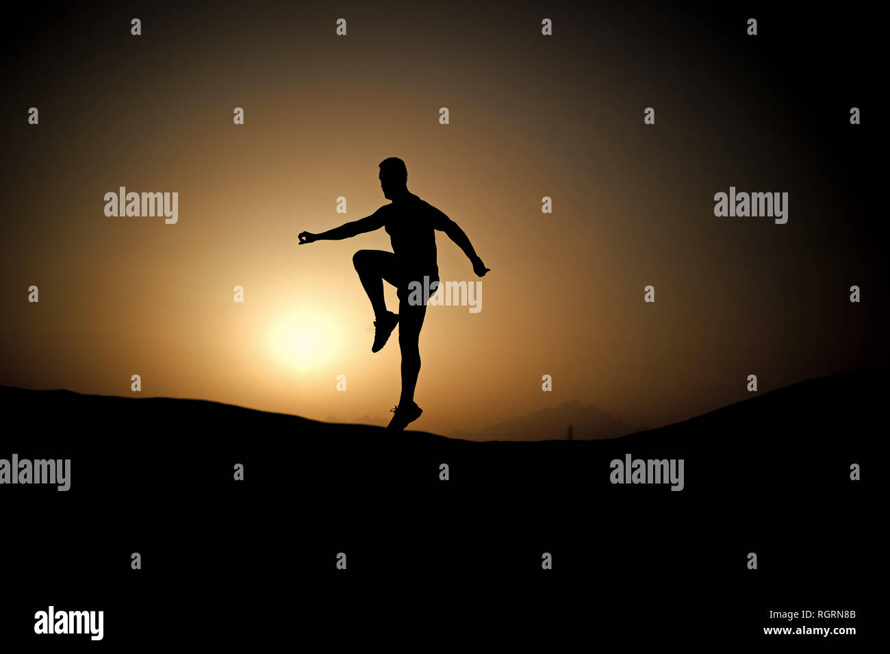 Athlete with muscular body in dusk. Man jump on sunset sky background ...