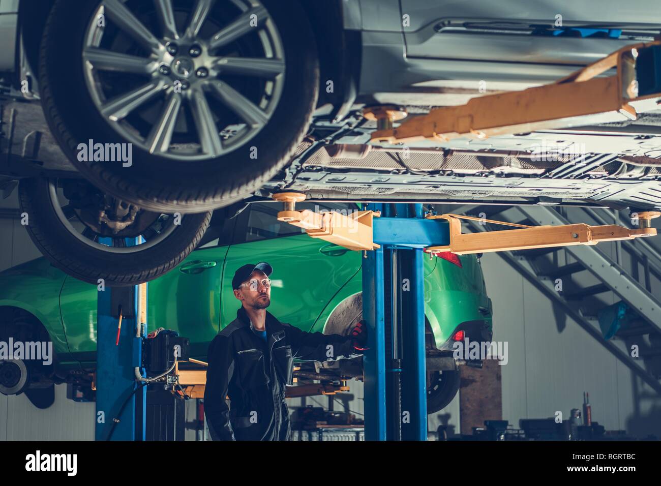 Modern Auto Service and Caucasian Car Mechanic. Broken Vehicles on a ...