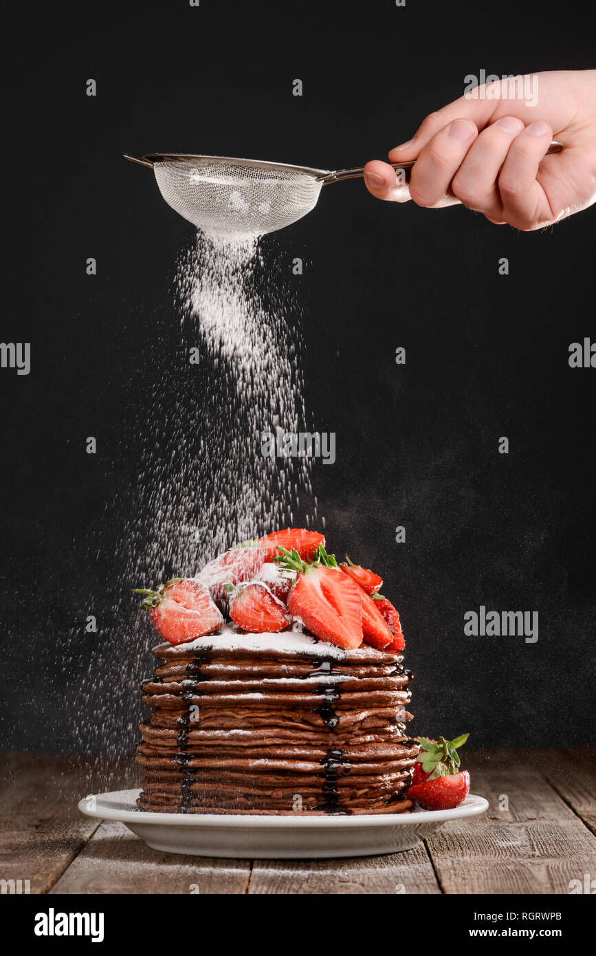 Hand sprinkles powdered sugar Stock Photo - Alamy
