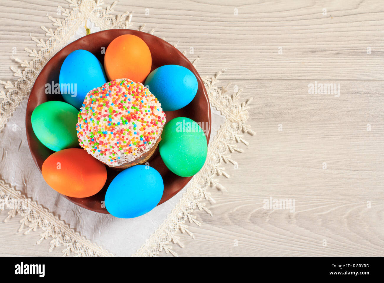 Easter cake and painted eggs on a plate with napkin and wooden boards ...