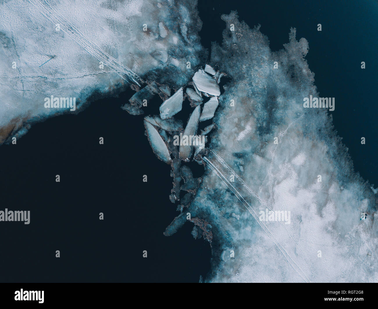 Broken ice plates floating in cold Arctic water near snowy coast shot ...