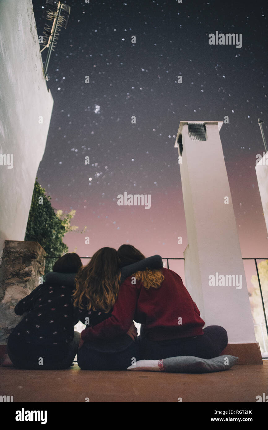 Back view of young friends hugging and admiring majestic starry sky ...