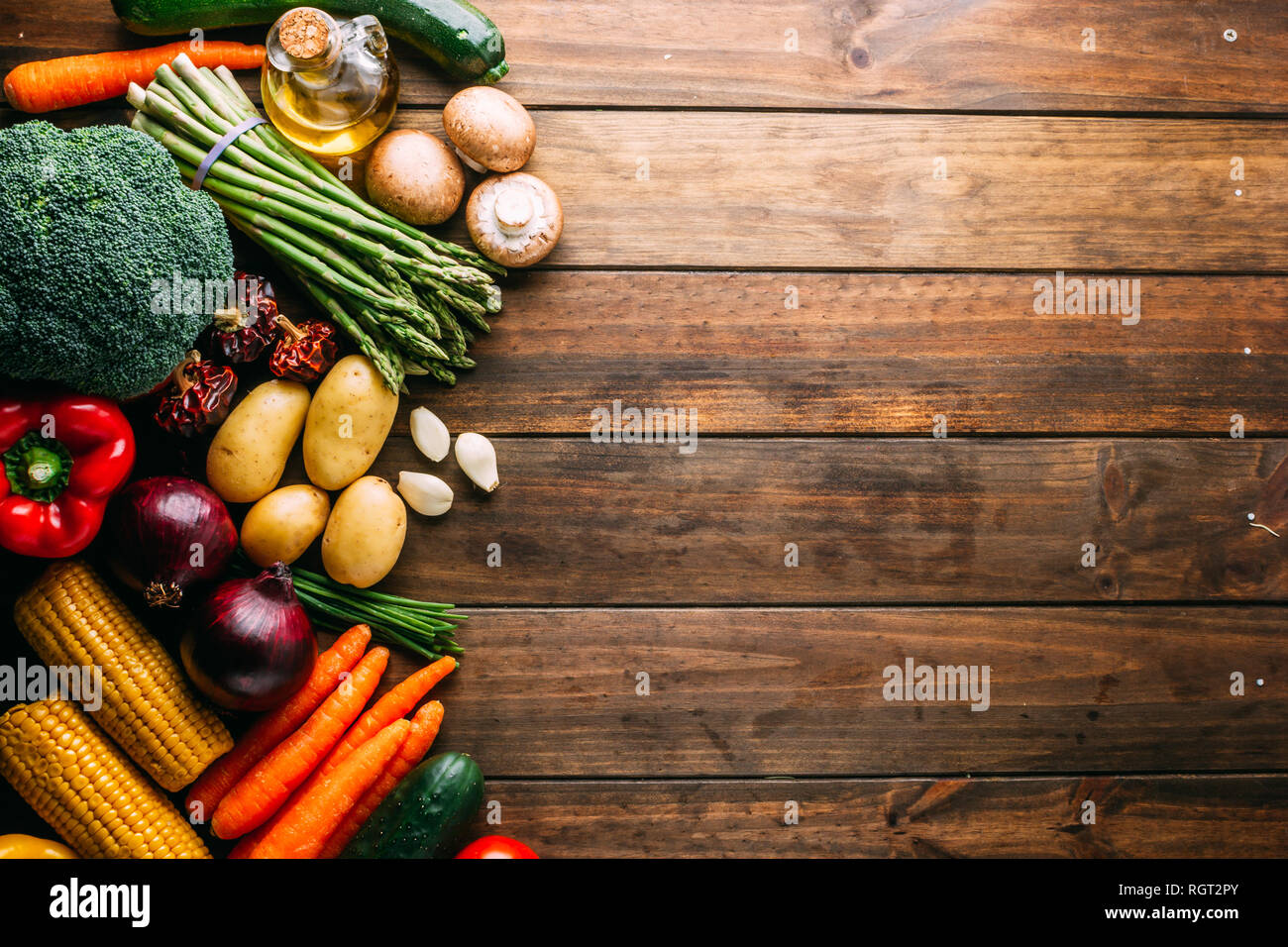 Set of assorted fresh vegetables lying near bottle of oil on side of ...