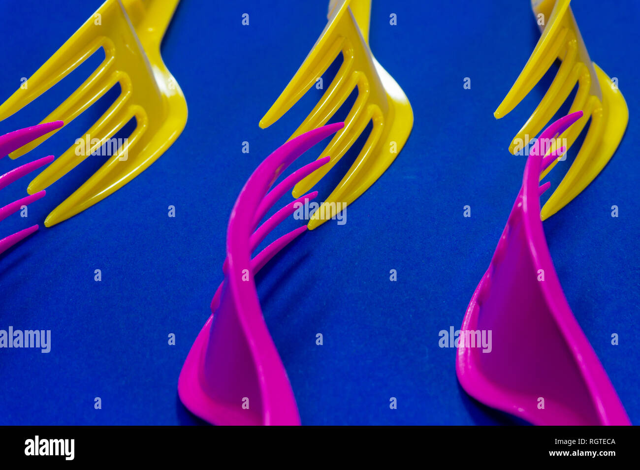 Pattern of colorful yellow and purple plastic forks laid end on end ...