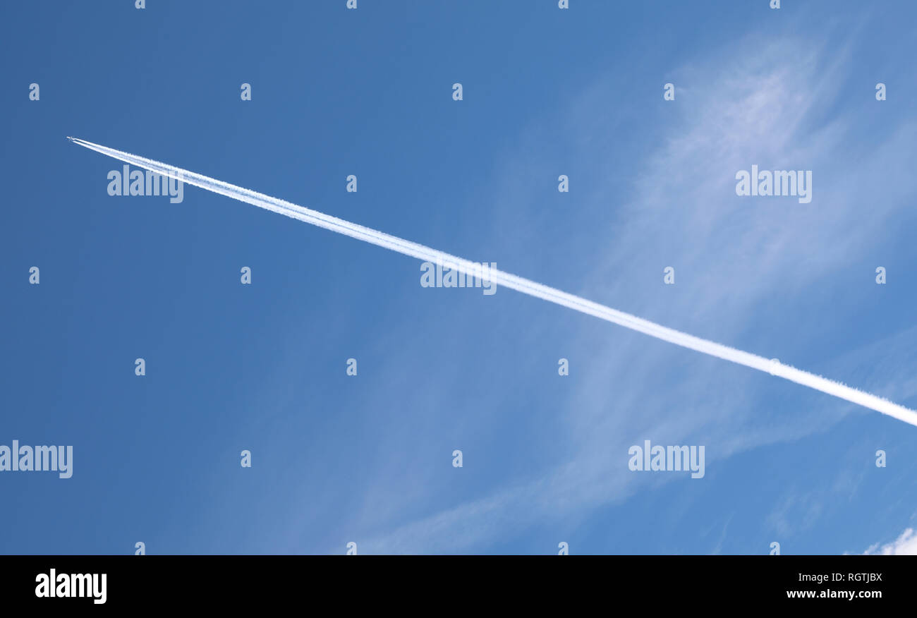 Engine exhaust contrails forming behind an airliner flying high in the ...