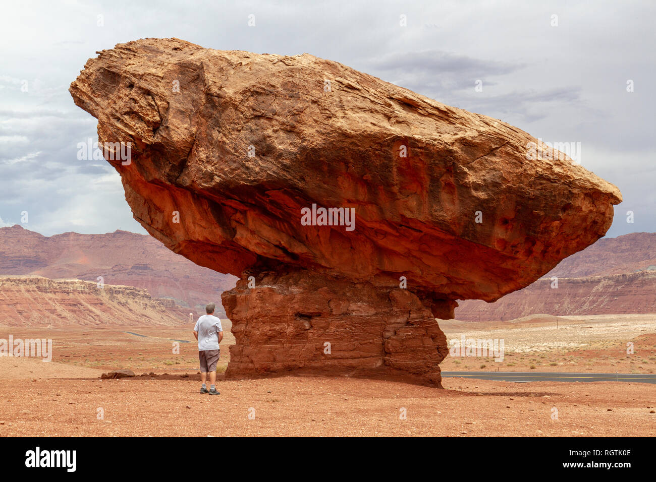 Visitor standing beside a balanced rock in Marble Canyon, Glen Canyon ...