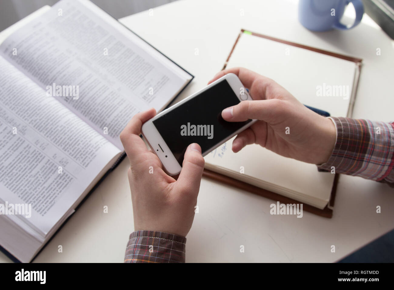 Teenage guy using phone while studying Stock Photo - Alamy
