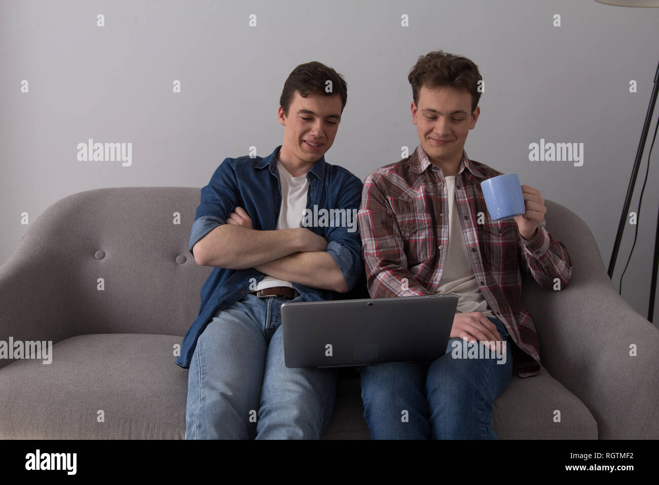 Two guys with laptop on sofa Stock Photo - Alamy