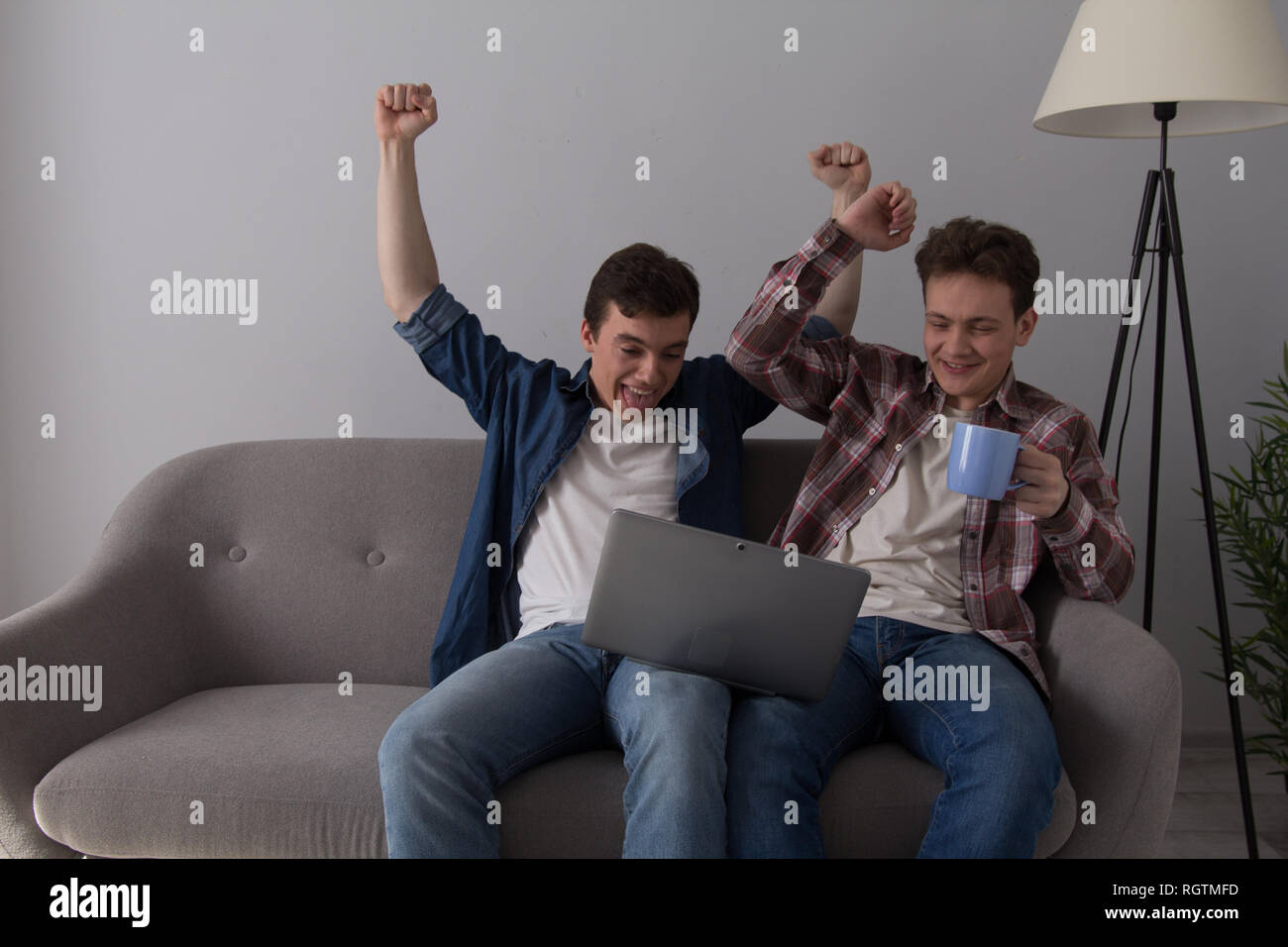 Two guys with laptop on sofa Stock Photo - Alamy
