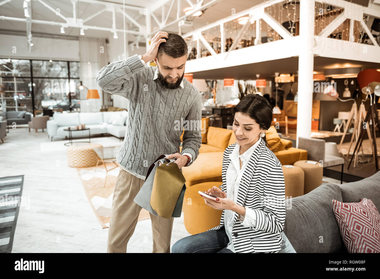 Long-haired tidy lady showing her husband designs on smartphone Stock ...