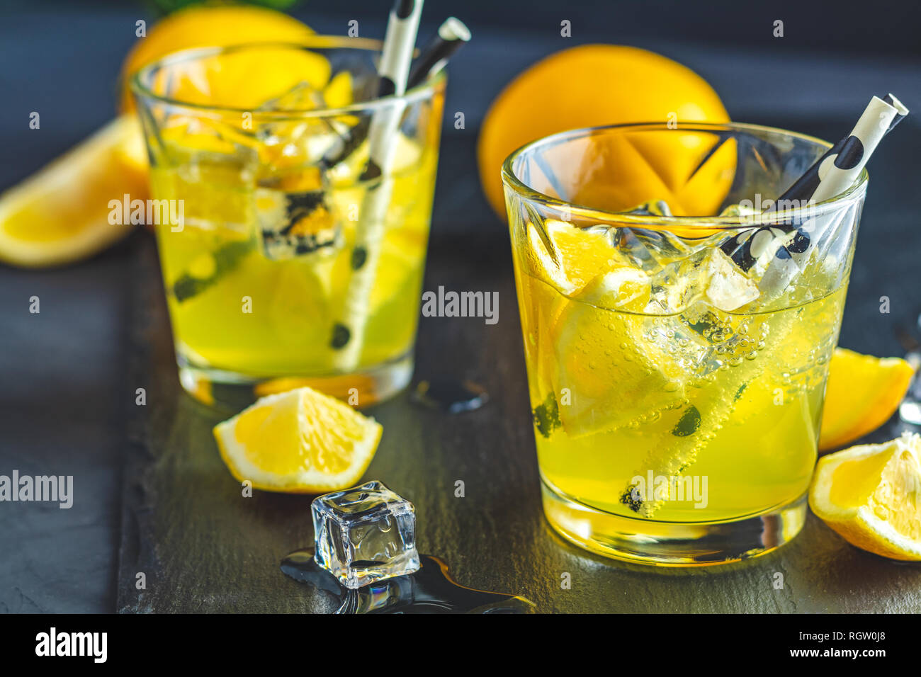 Lemon alcohol drink cocktail with ice, lemon and rosemary herb on black ...