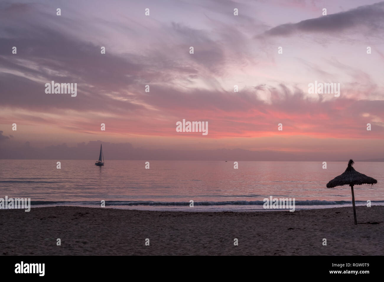 Sailboat anchored offshore close to sandy beach creates vision tension ...