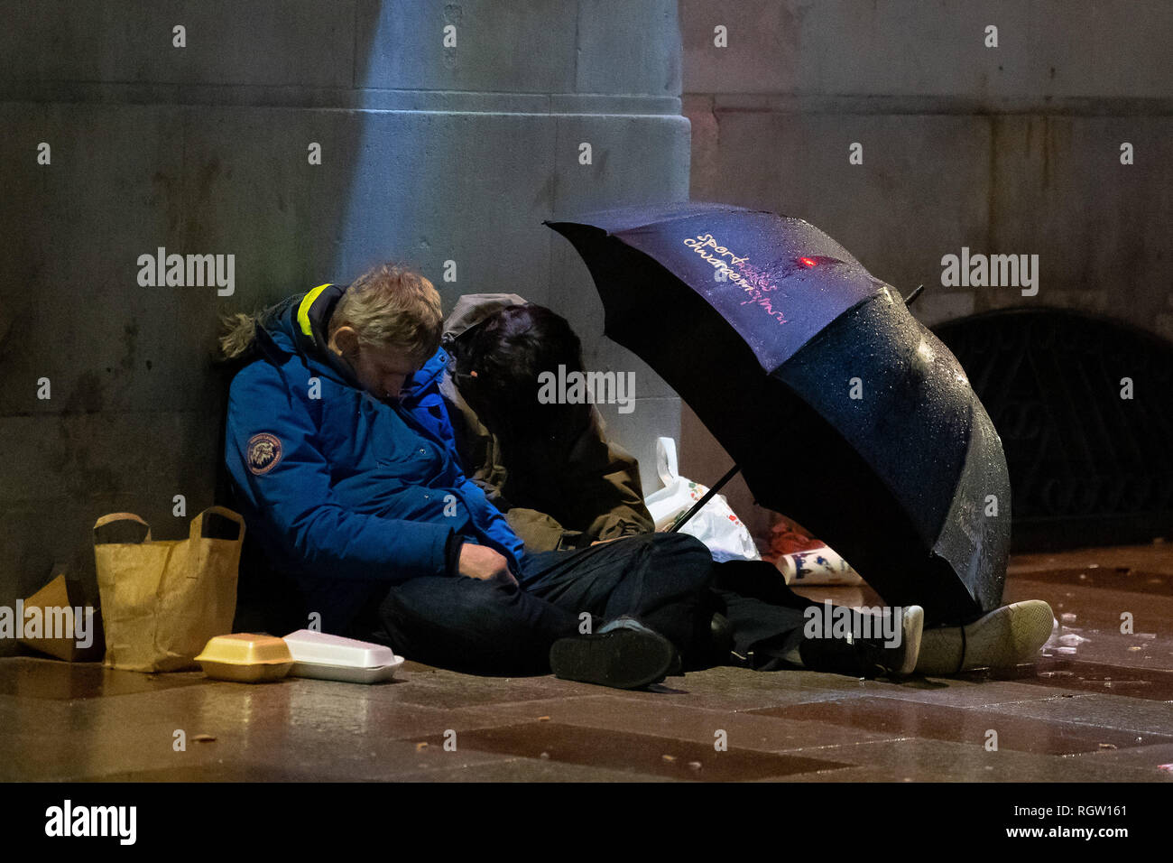 Two homeless people shelter near a tent at night on St. Mary’s Street ...