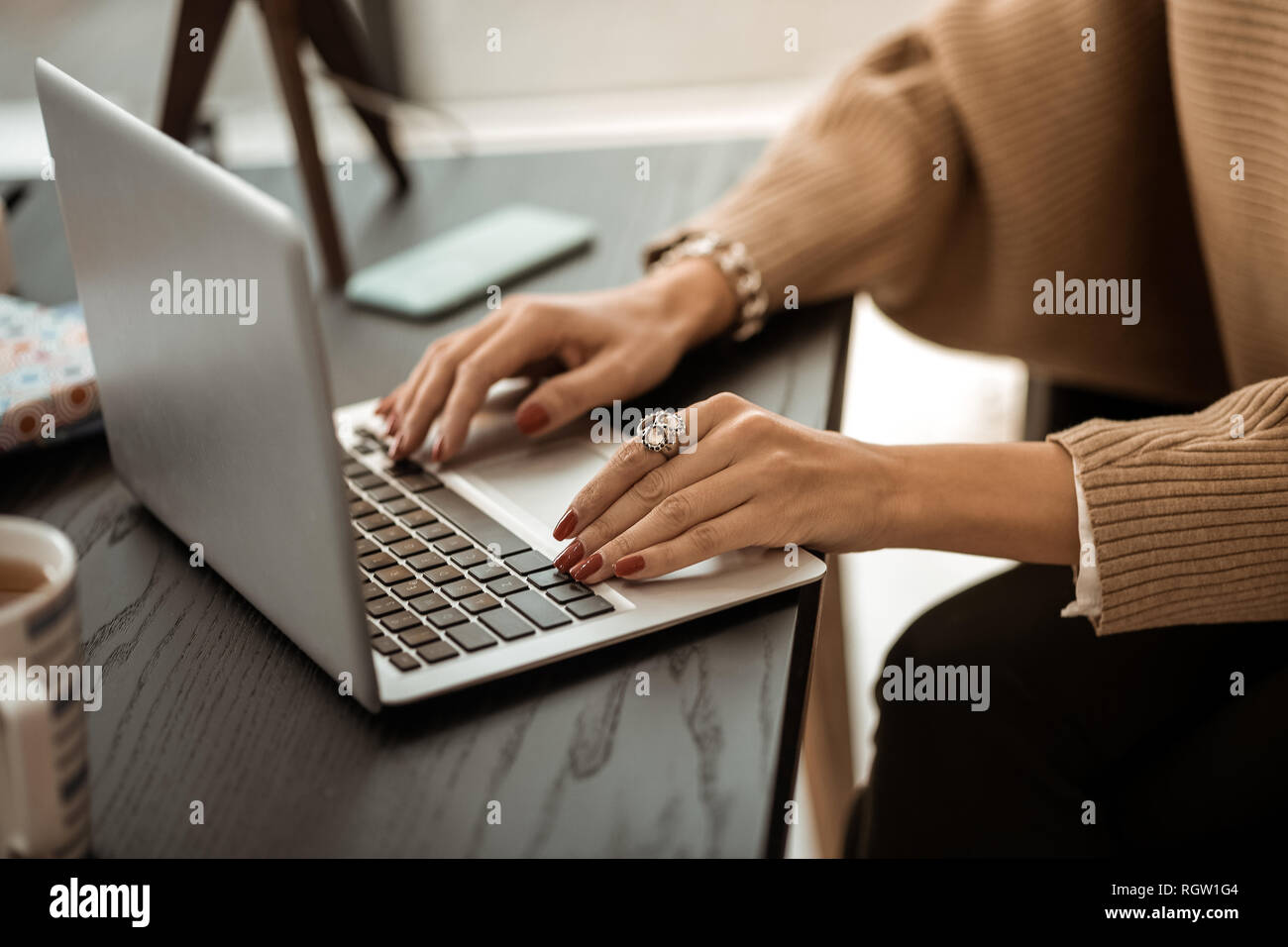 Tidy woman in beige sweater with red manicure Stock Photo - Alamy