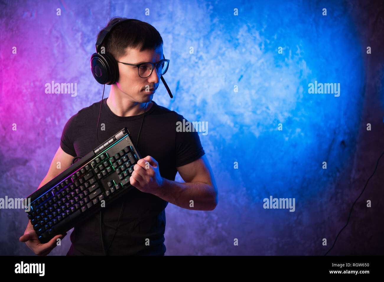 Professional Boy Gamer holding gaming keyboard over colorful pink and ...
