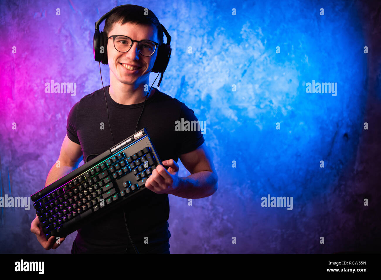 Professional Boy Gamer holding gaming keyboard over colorful pink and ...