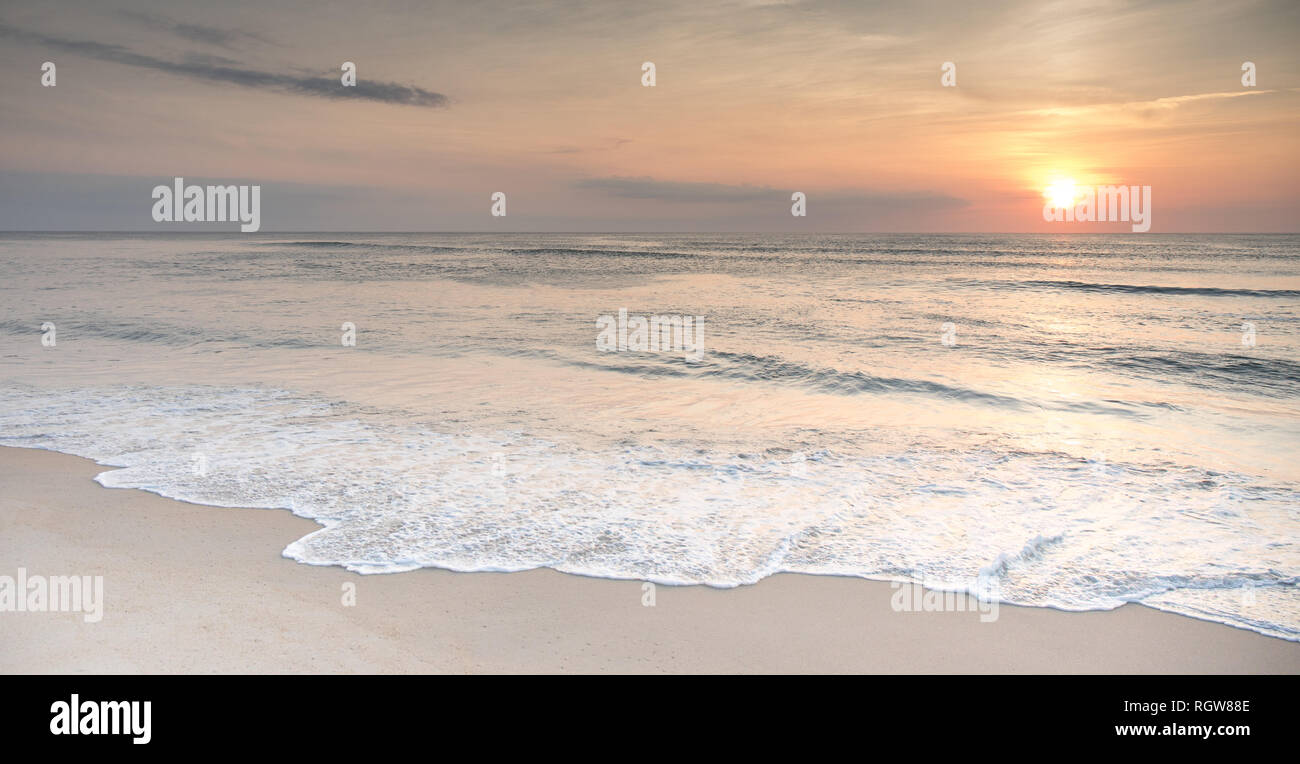 The sun rising over the ocean at sunrise with waves crashing ashore ...