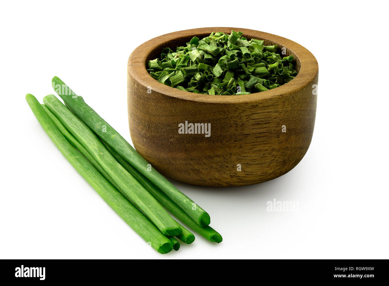 Dried chopped chives in a dark wood bowl next to a pile of whole fresh ...