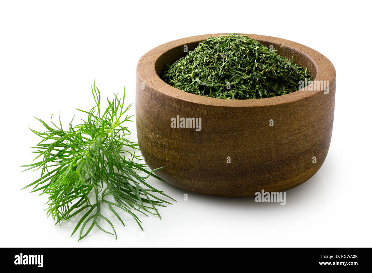 Dried chopped dill in a dark wood bowl next to fresh dill leaves ...