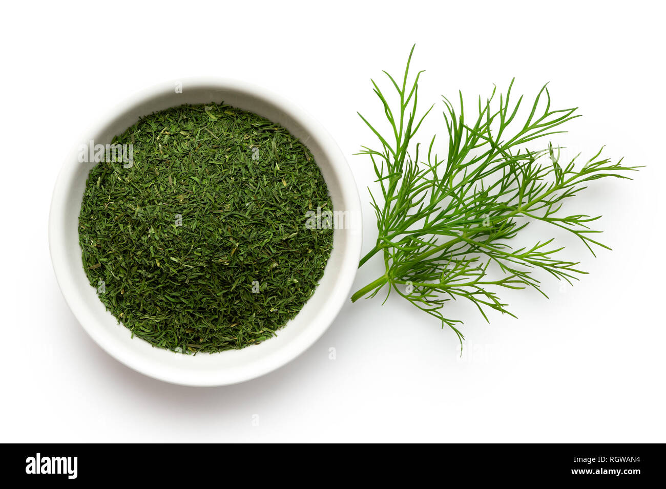 Dried chopped dill in white ceramic bowl next to fresh dill leaves ...