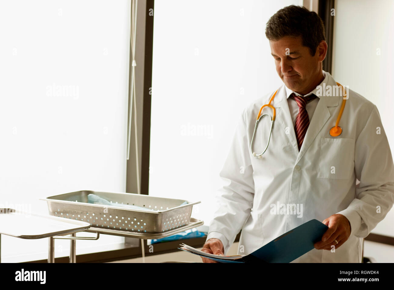 Male doctor reading patient files Stock Photo - Alamy