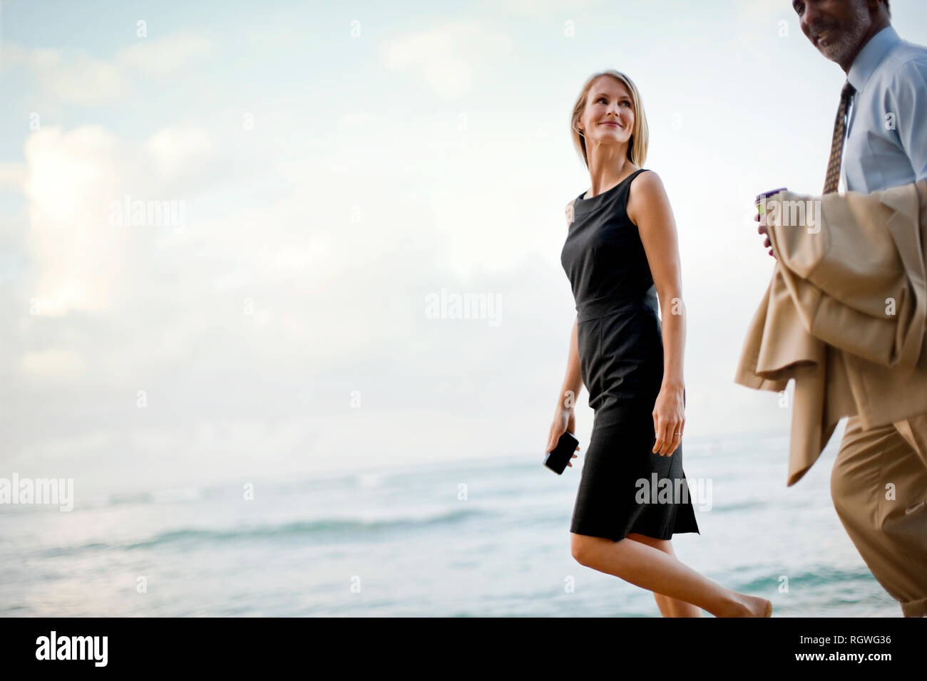 Two business partners enjoy walking on the beach together Stock Photo ...