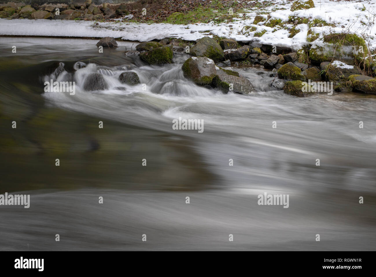 A small river flowing between trees with a small water degree. The ...