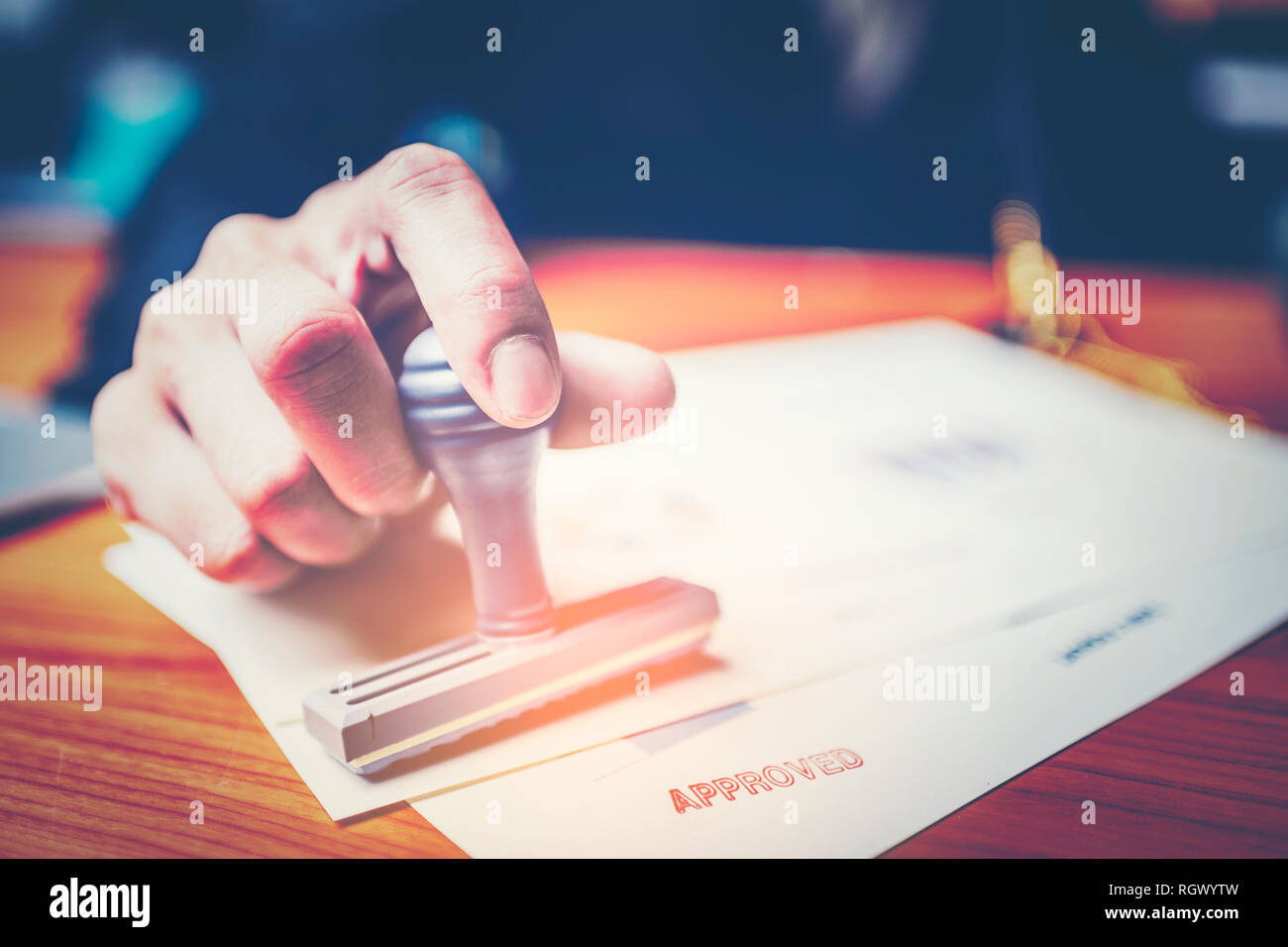 Close-up hand stamping of businessman for signing approval on documents ...