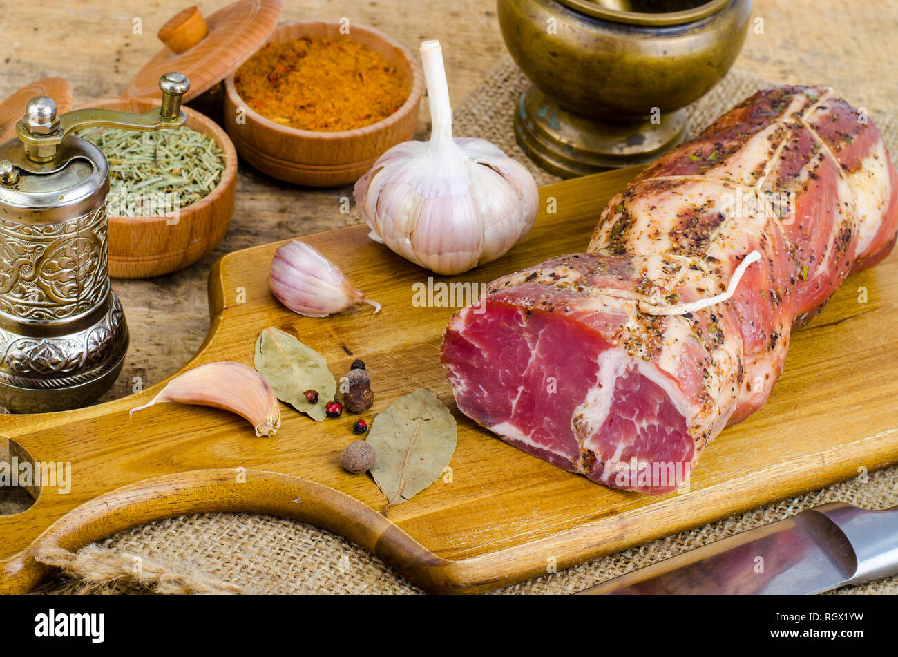 Traditional smoked pork neck with herbs and spices on wooden table ...